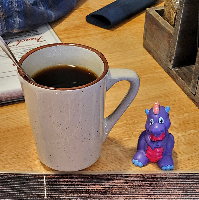 Coffee served in a mug with character, accompanied by what appears to be a lucky dragon. Some mornings require both caffeine and a little magic.