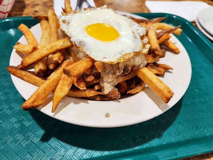 Fries supporting the weight of expectations—and a perfectly fried egg. This mountain of potato goodness is what comfort food aspiration looks like.