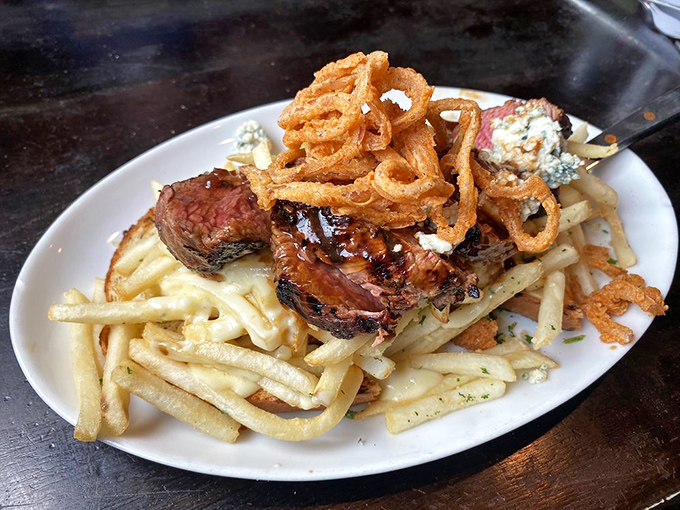 Perfectly seared steak atop golden fries with those crispy onion rings perched like delicious halos – this plate doesn't just satisfy hunger, it conquers it.
