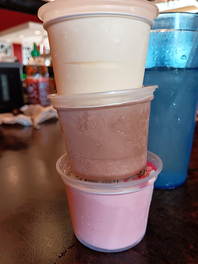 Dessert cups stacked like a tower of sweet possibilities. Vanilla, chocolate, and strawberry—the Neapolitan trifecta of happiness in convenient to-go form.