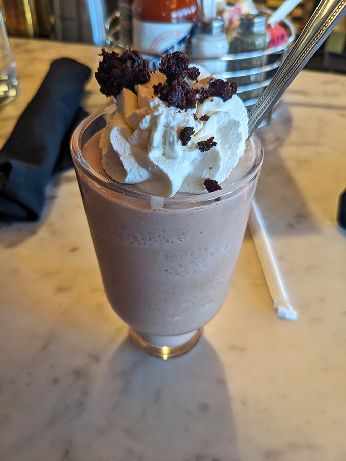 A milkshake that understands excess is sometimes exactly right—topped with whipped cream and brownie chunks, it's dessert masquerading as a beverage.