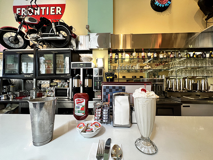 A milkshake so thick it laughs at straws, served with the metal mixing cup—because leaving extra milkshake behind would be a crime against humanity.