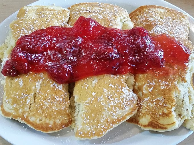 Pancakes wearing their strawberry topping like a crown. Breakfast royalty that doesn't stand on ceremony – just maple syrup.