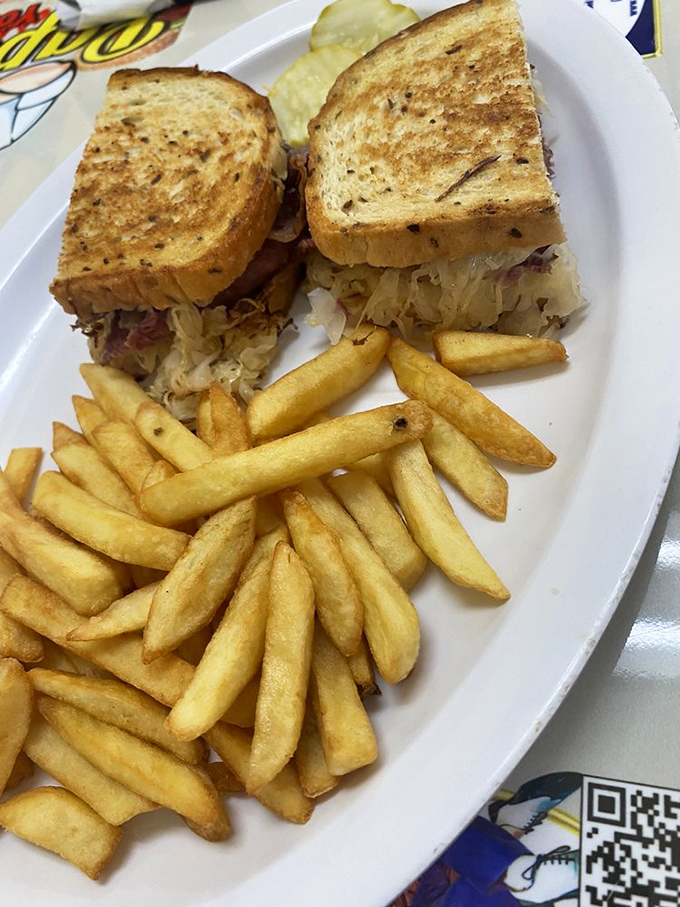 The Reuben sandwich—where corned beef, sauerkraut, and grilled rye bread create the holy trinity of deli perfection with fries as faithful disciples.