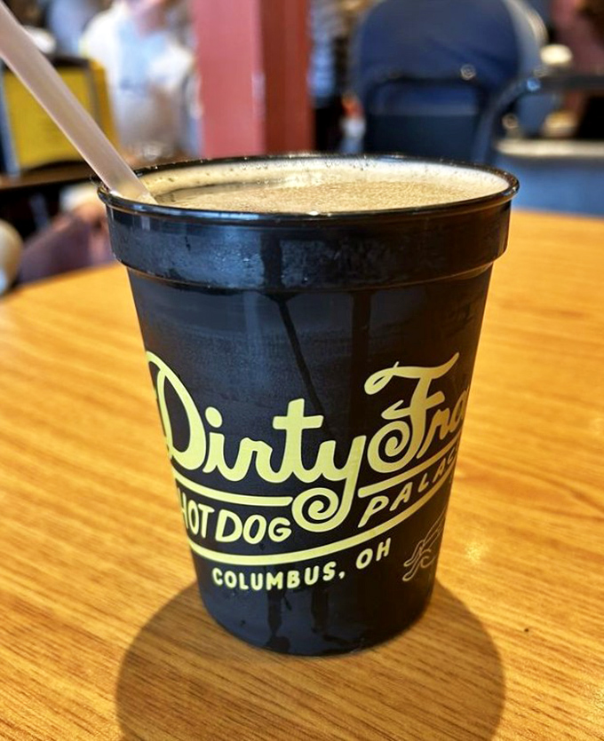 That iconic black cup holds liquid memories—a root beer that pairs with everything on the menu like they were soul mates in a previous life.