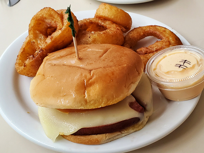 The classic cheeseburger and onion rings combo—proof that sometimes the simplest pleasures are the most profound. Nostalgic deliciousness on a white plate.