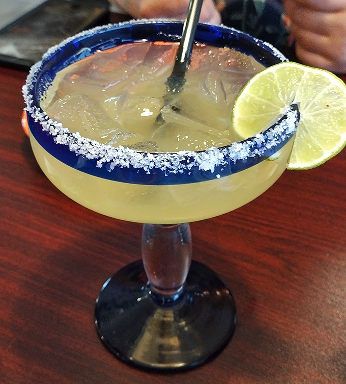 The margarita's salt rim isn't just decoration—it's the perfect prelude to that sweet-tart symphony waiting inside the blue-rimmed glass.