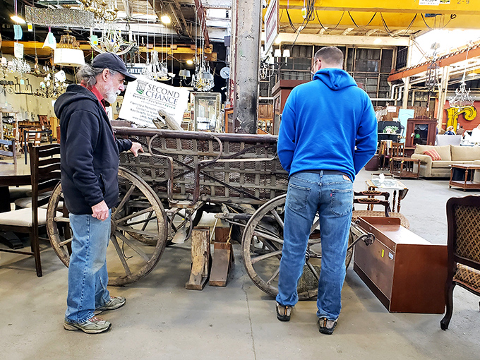 Two treasure hunters contemplating what appears to be a vintage wagon—proof that at Second Chance, "impulse buy" can mean anything from a doorknob to a horse-drawn carriage.