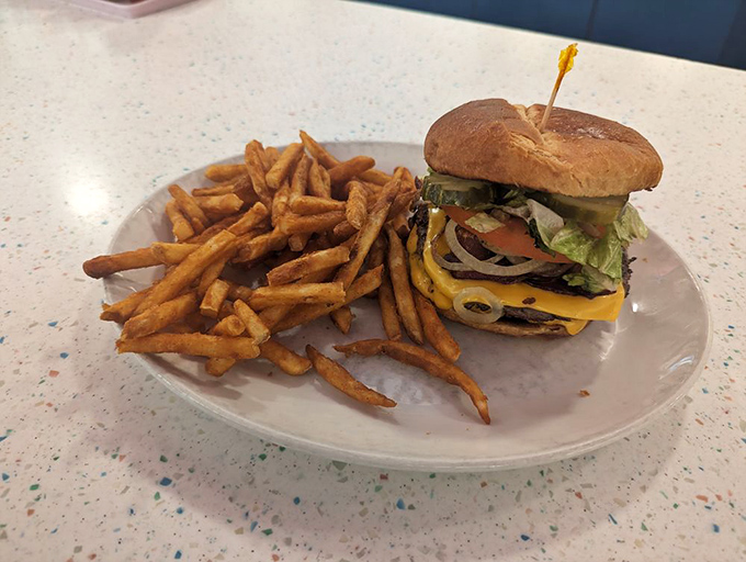 This burger doesn't just satisfy hunger—it obliterates it. Golden fries stand at attention alongside their beefy commander-in-chief.