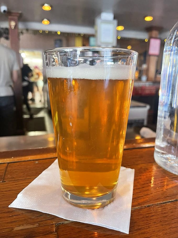 A cold beer on a wooden bar—civilization's oldest and most reliable antidote to the 40-minute wait for your deep dish masterpiece.