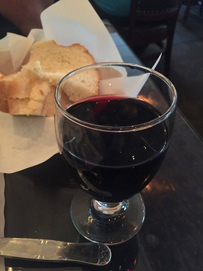 A glass of house red that doesn't pretend to be fancy, paired with bread that exists solely to soak up every last drop of sauce on your plate.