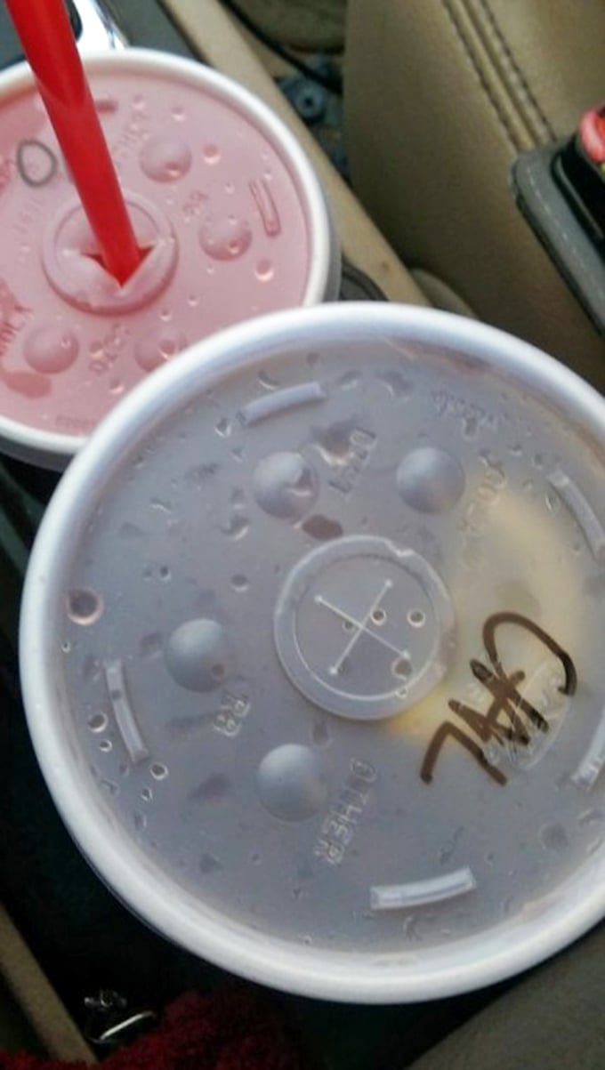 Two frosty shakes sitting in the car cupholder—one pink, one white—waiting to deliver brain freeze that's somehow worth every chilly second.