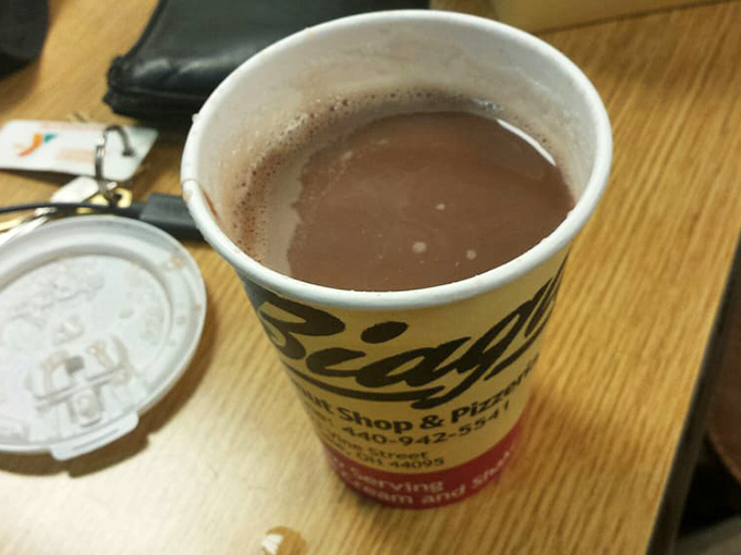 Hot chocolate served in a no-nonsense cup—comfort in liquid form that pairs perfectly with whatever's in that pink box.