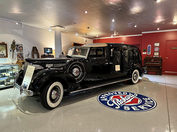 Parked on a Packard Service floor medallion, this 1938 Packard hearse represents American automotive craftsmanship at its finest—luxury transportation for the ultimate one-way trip.