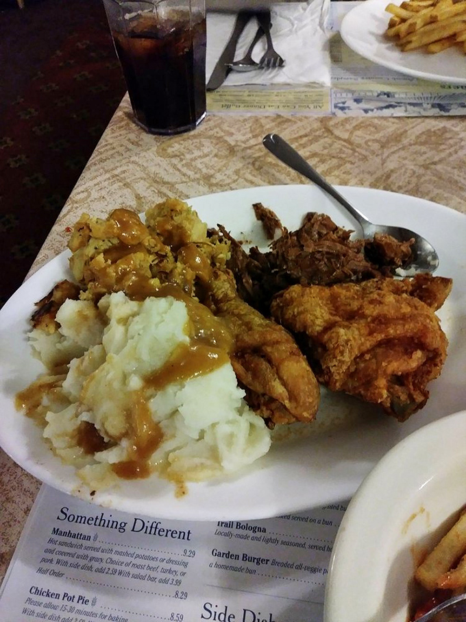 The Amish Country Sampler plate—where mashed potatoes become a gravy lake, fried chicken stands proud, and diet plans go to die happily.