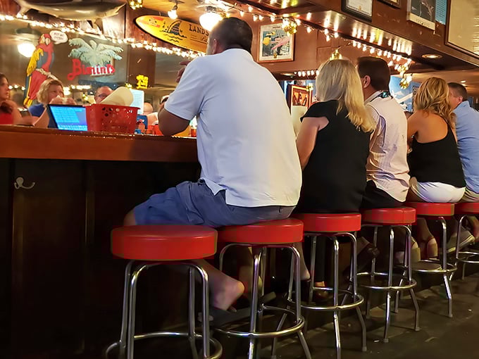 The red bar stools aren't just seating – they're front-row tickets to the best show in town: watching bartenders work their magic.