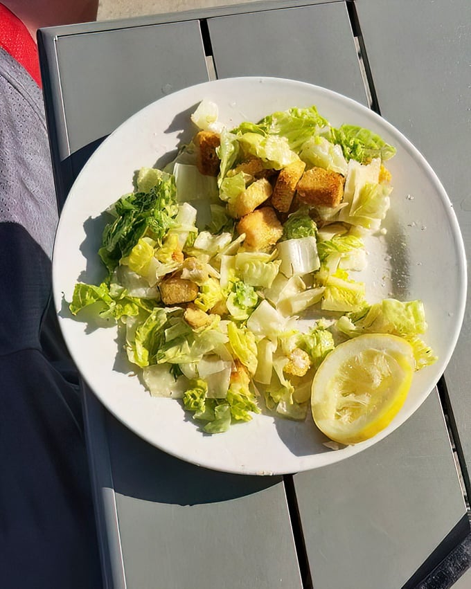 Caesar salad so fresh and bright it could convince a committed carnivore to consider a day without meat. That lemon wedge isn't just garnish—it's essential punctuation.