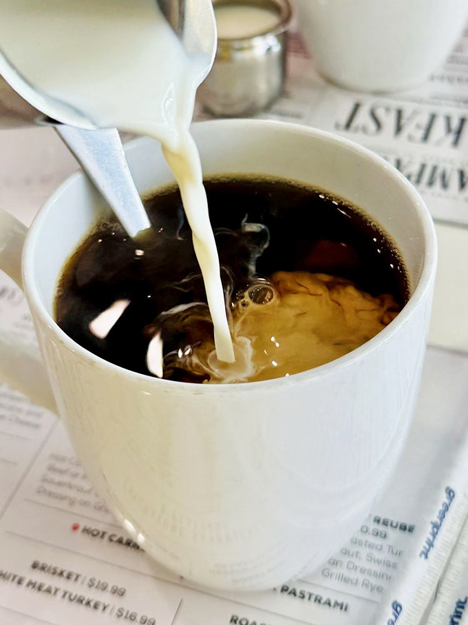 The perfect coffee pour – that mesmerizing dance of cream meeting dark brew. A necessary companion for bagel contemplation.