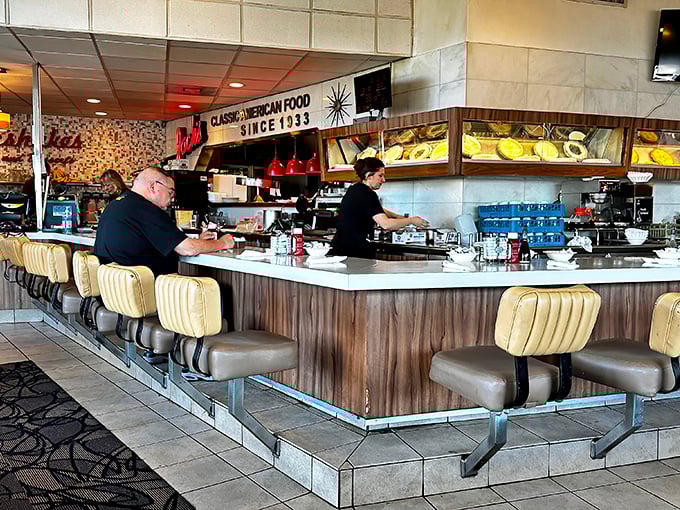 The counter seats—where regulars become family and solo diners never feel alone. This is the VIP section of comfort food theater.