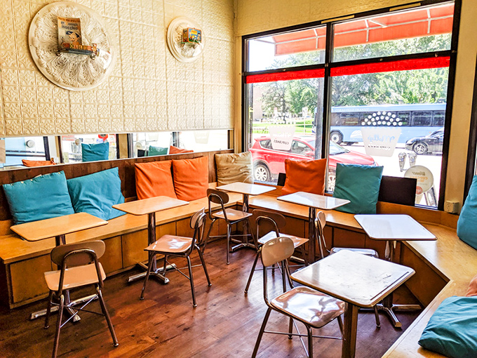 Colorful pillows line bench seating by sun-drenched windows, creating the perfect spot to contemplate life's important questions—like which cupcake to try next.