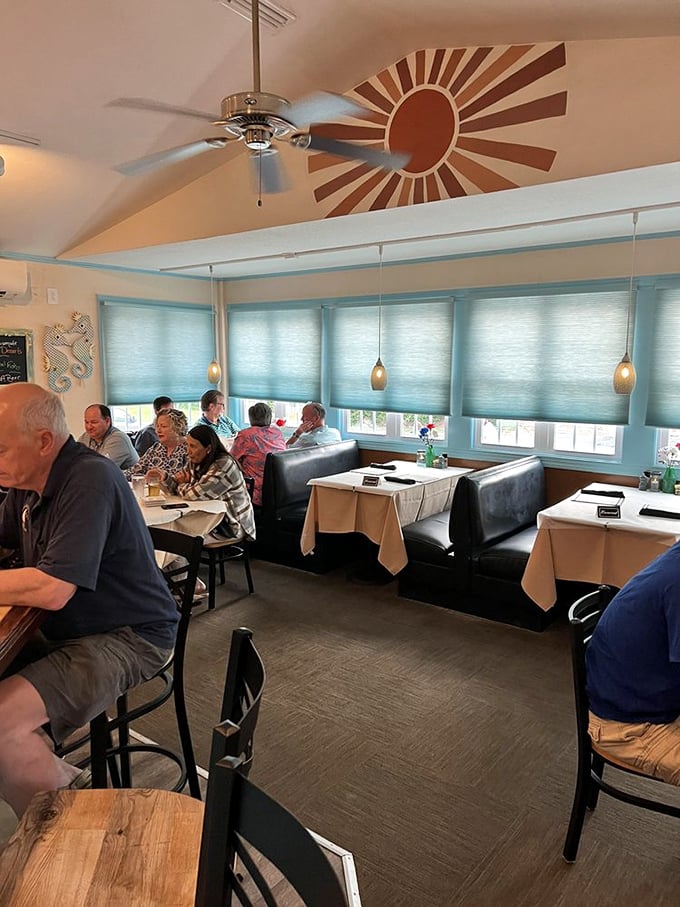 Sunburst ceiling art watches over diners like a benevolent coastal deity. The blue accents and booth seating create the perfect backdrop for seafood revelations.