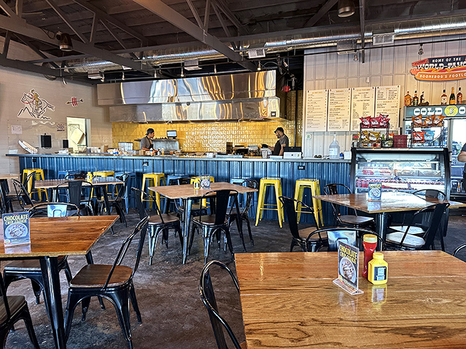 The dining area balances industrial elements with warmth—blue counter, wooden tables, and enough space to accommodate both quiet conversations and boisterous gatherings.