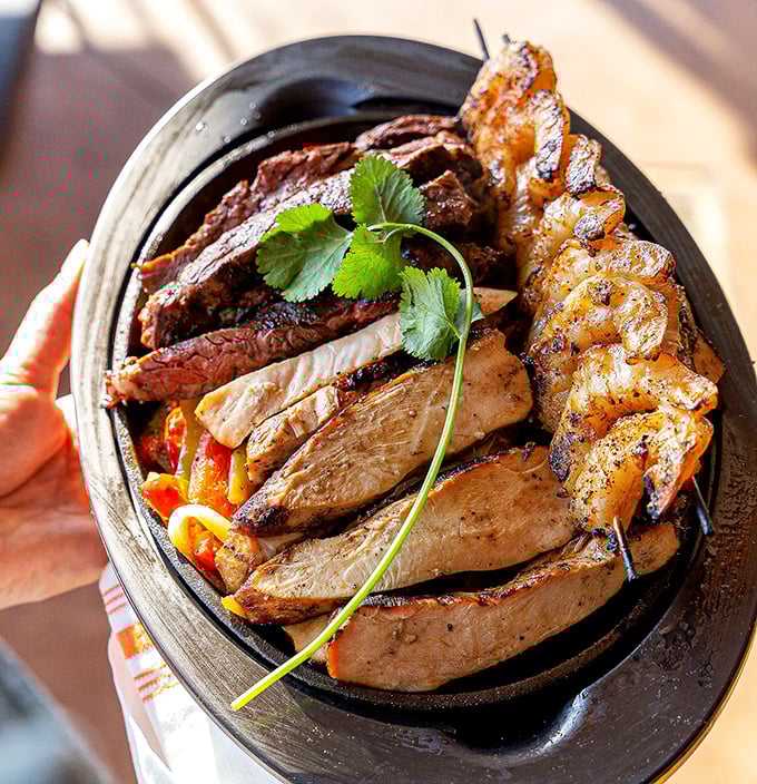 The fajita triple threat – a sizzling cast iron skillet where beef, chicken, and shrimp perform a smoky, spice-infused dance that's worth the front-row seat.