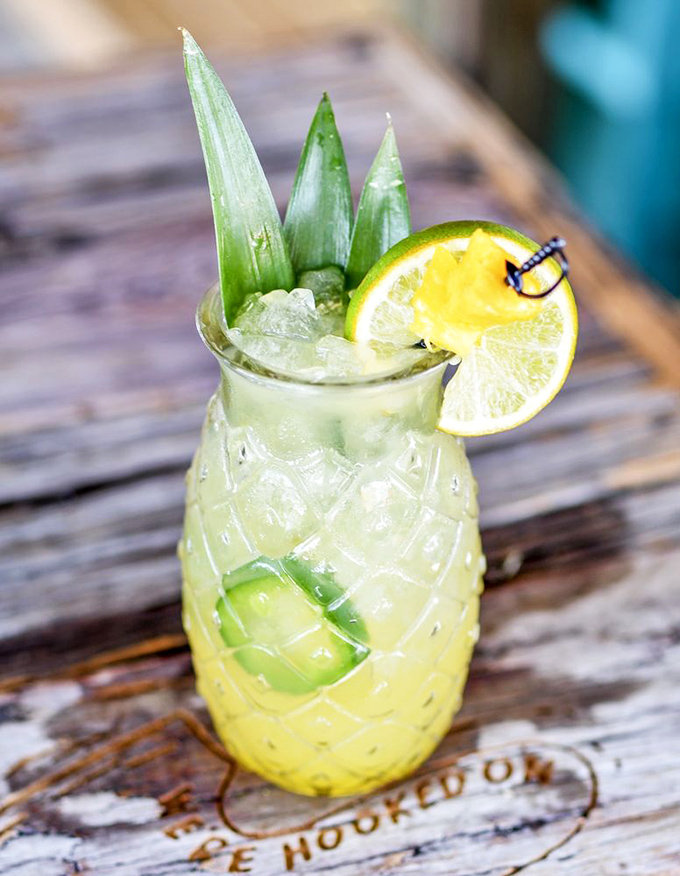 A pineapple vessel transforms an ordinary cocktail into a vacation in a glass—complete with tiny paper umbrella real estate.