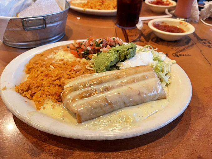 This chimichanga isn't just wrapped in a tortilla—it's wrapped in a blanket of queso that makes you want to send a thank-you note to whoever invented cheese.