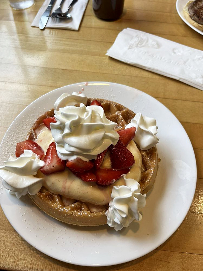 A waffle that's dressed for success with strawberries, bananas, and whipped cream – breakfast masquerading as dessert, and nobody's complaining.