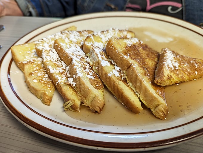 French toast that's achieved the impossible balance—crispy edges, custardy centers, and a dusting of powdered sugar that falls like delicious snow.