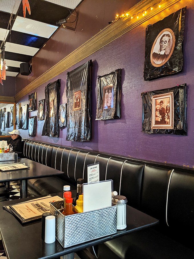 The purple walls adorned with vintage portraits create an atmosphere that's part haunted mansion, part cozy diner—somehow it works perfectly.