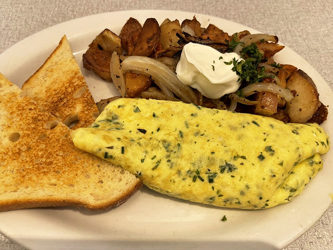 This isn't just an omelet—it's a fluffy yellow envelope delivering herbs and cheese alongside potatoes that have clearly been on a first-name basis with butter.