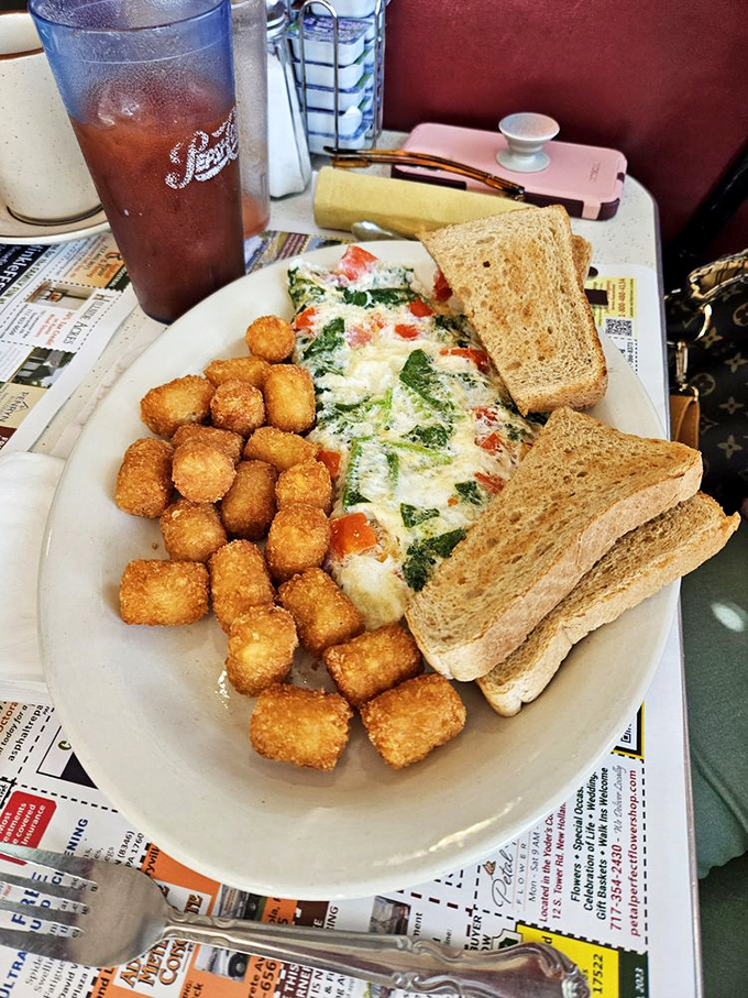 This omelet with tater tots isn't just breakfast—it's edible architecture. The perfect trinity of eggs, potatoes, and toast that screams "Good morning, indeed!"