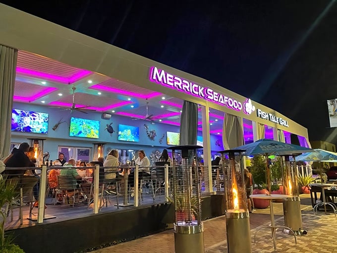 The neon-lit exterior of Fish Tale Grill beckons like a lighthouse for hungry seafood lovers. Purple lighting transforms this Cape Coral hotspot into an underwater fantasy after dark.