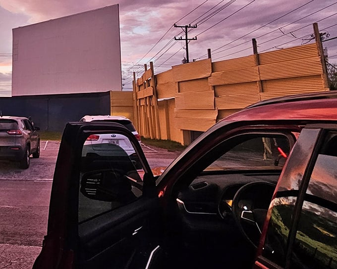 The American flag glows on screen as pickup trucks and sedans settle in for showtime. Movie magic meets patriotic pride under the Florida stars.