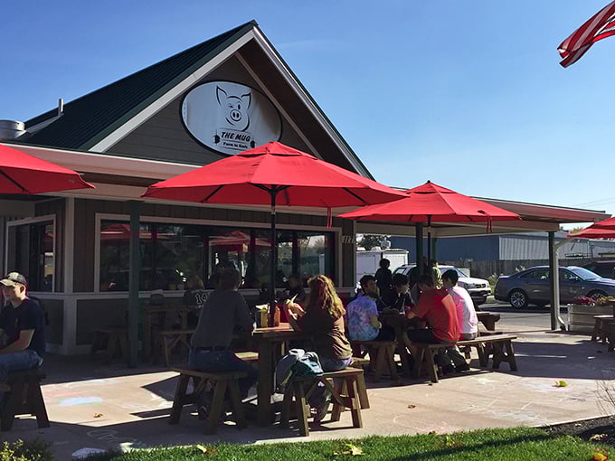 The Mug's inviting exterior with its bright red umbrellas practically whispers, "Come sit a spell." Small-town charm with big-time flavor potential.
