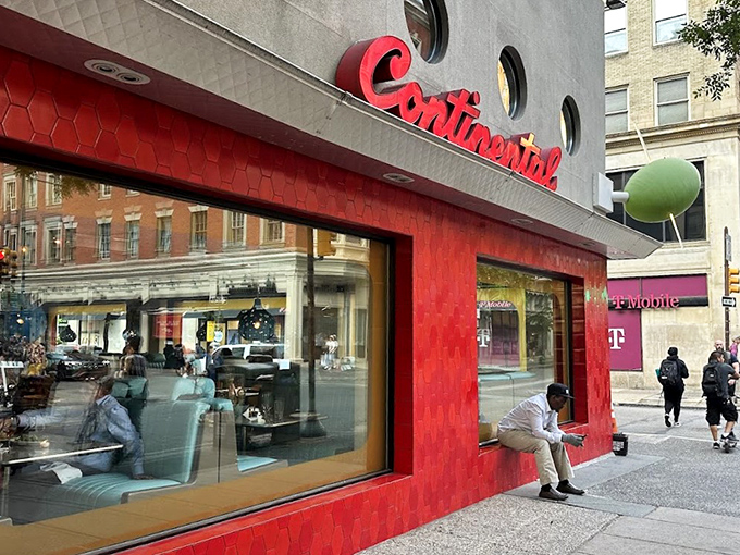 The Continental's iconic red façade with porthole windows stands like a retro spaceship that landed in Rittenhouse Square, promising culinary adventures within.