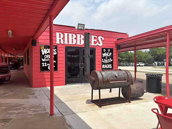 The bright red exterior of Ribbee's isn't subtle – it's like Texas itself, boldly announcing "serious barbecue happens here" with its weathered smoker standing guard.