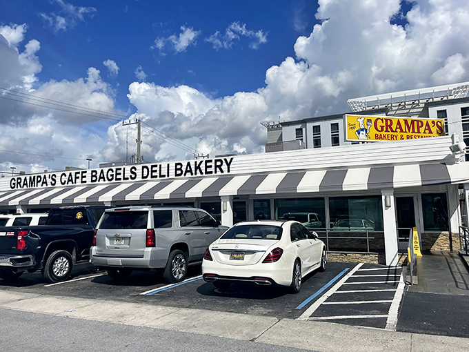 The classic black-and-white striped awning isn't just retro charm—it's a beacon for bagel lovers across South Florida. Grampa's exterior promises New York authenticity under swaying palm trees.