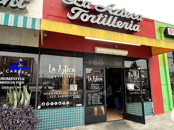 The vibrant red and yellow façade of La Azteca Tortilleria stands like a beacon of culinary promise on Cesar Chavez Avenue.