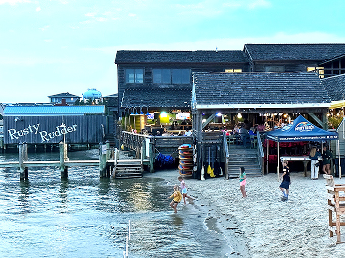 Where land meets water and hunger meets satisfaction—the Rusty Rudder's weathered exterior promises seafood treasures just steps from Rehoboth Bay.