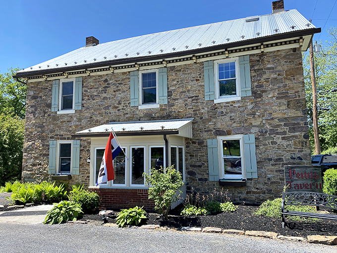 Stone walls that have witnessed centuries of American history stand proudly under a metal roof, with pale blue shutters adding colonial charm to this riverside treasure.