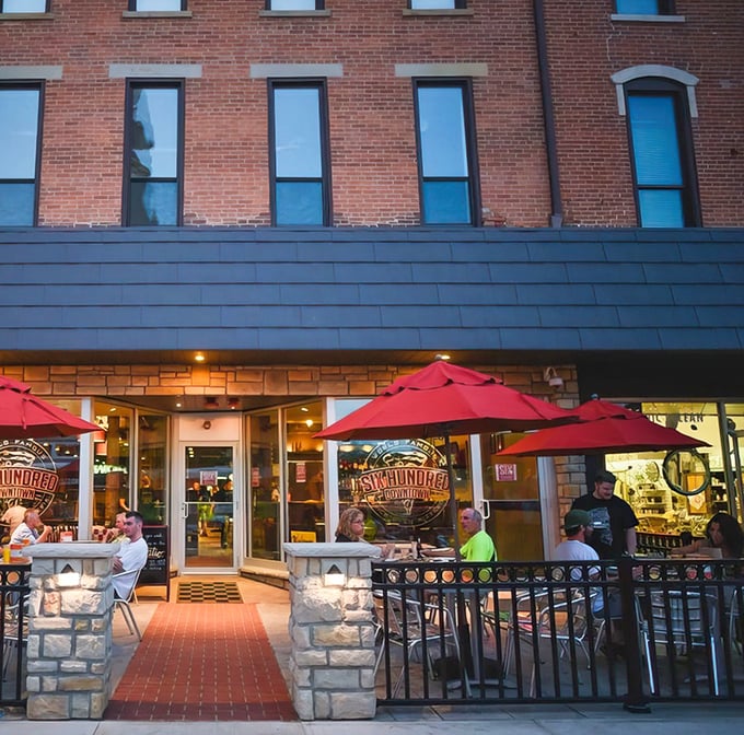 The historic brick façade of Six Hundred Downtown welcomes pizza pilgrims with its cheerful red umbrellas and inviting patio seating.