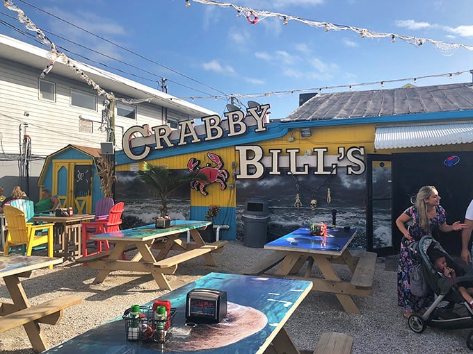 The colorful exterior of Crabby Bill's screams "Florida seafood joint" with its vibrant picnic tables and that iconic crab sign beckoning hungry beachgoers.