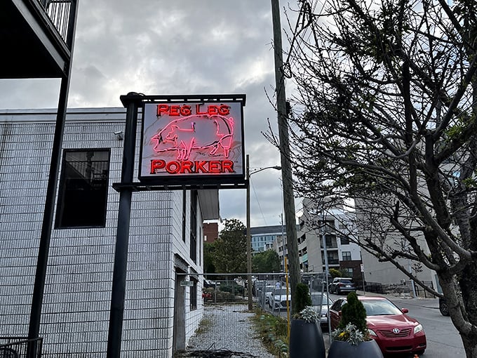 The neon pig sign glows like a beacon of barbecue hope in Nashville's Gulch neighborhood, promising smoky delights within these unassuming walls.