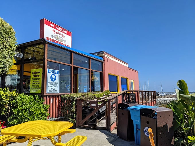 The iconic red exterior of Barbara's Fishtrap stands like a colorful sentinel against the Half Moon Bay coastline, promising seafood treasures within.