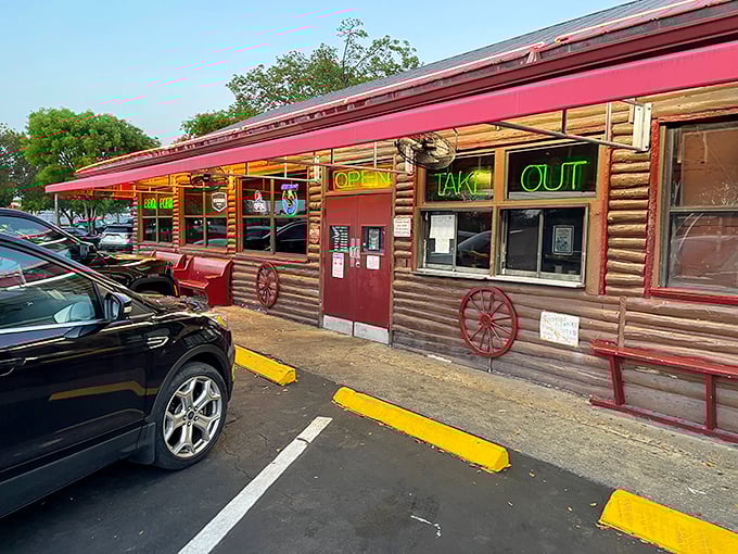 That neon glow isn't just for show—it's a barbecue beacon calling hungry souls to this log cabin sanctuary where smoke signals promise delicious things ahead.