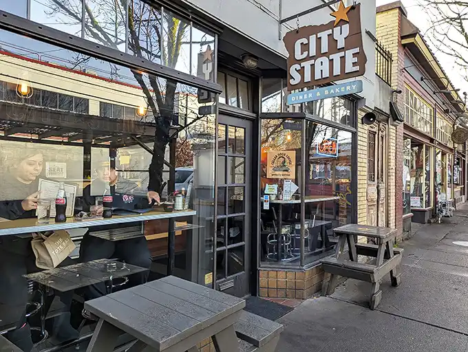 The iconic Oregon-shaped sign welcomes hungry patrons to City State Diner & Bakery, where Portland's breakfast dreams come true under leafy neighborhood trees.