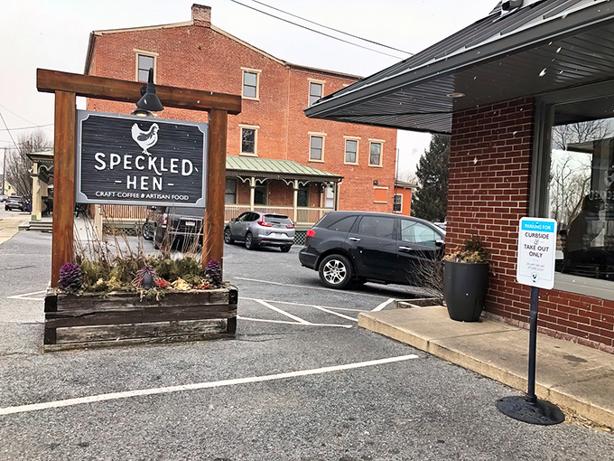 The unassuming brick exterior of Speckled Hen hides culinary treasures within. That wooden sign promises craft coffee and artisan food—spoiler alert: it delivers both spectacularly.
